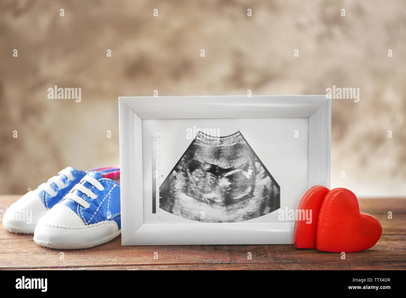 Ultrasound picture of baby in photo frame and children shoes on table ...