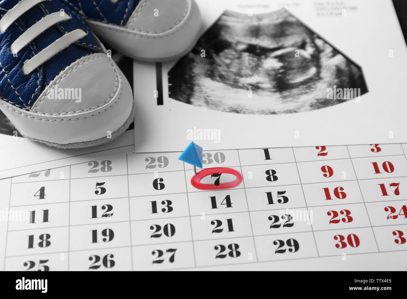 Calendar with ultrasound scan of baby and children shoes, closeup Stock ...