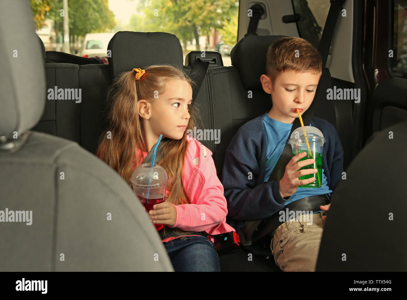 Cute children drinking in a car Stock Photo - Alamy