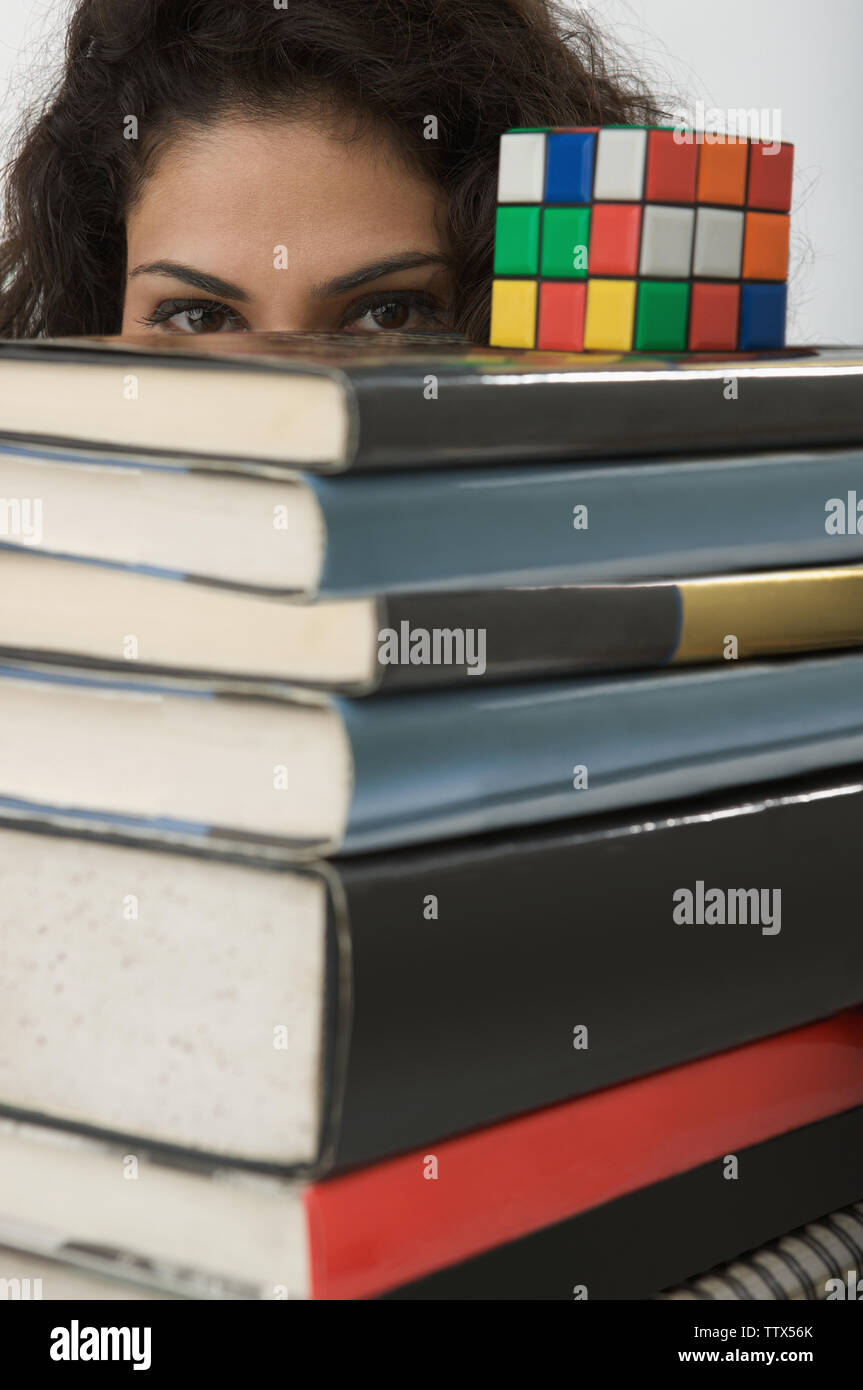Woman looking over a stack of books Stock Photo - Alamy