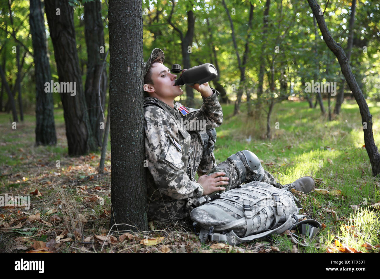 Soldier drinking water from canteen in forest Stock Photo - Alamy