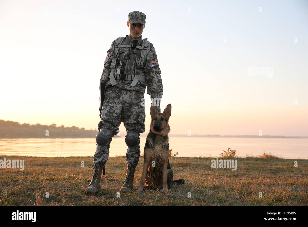 Soldier with german shepherd dog near river at sunset Stock Photo - Alamy