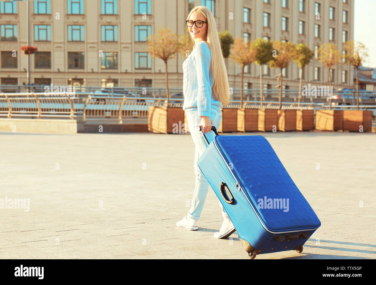 Young woman with big blue trunk on street Stock Photo - Alamy