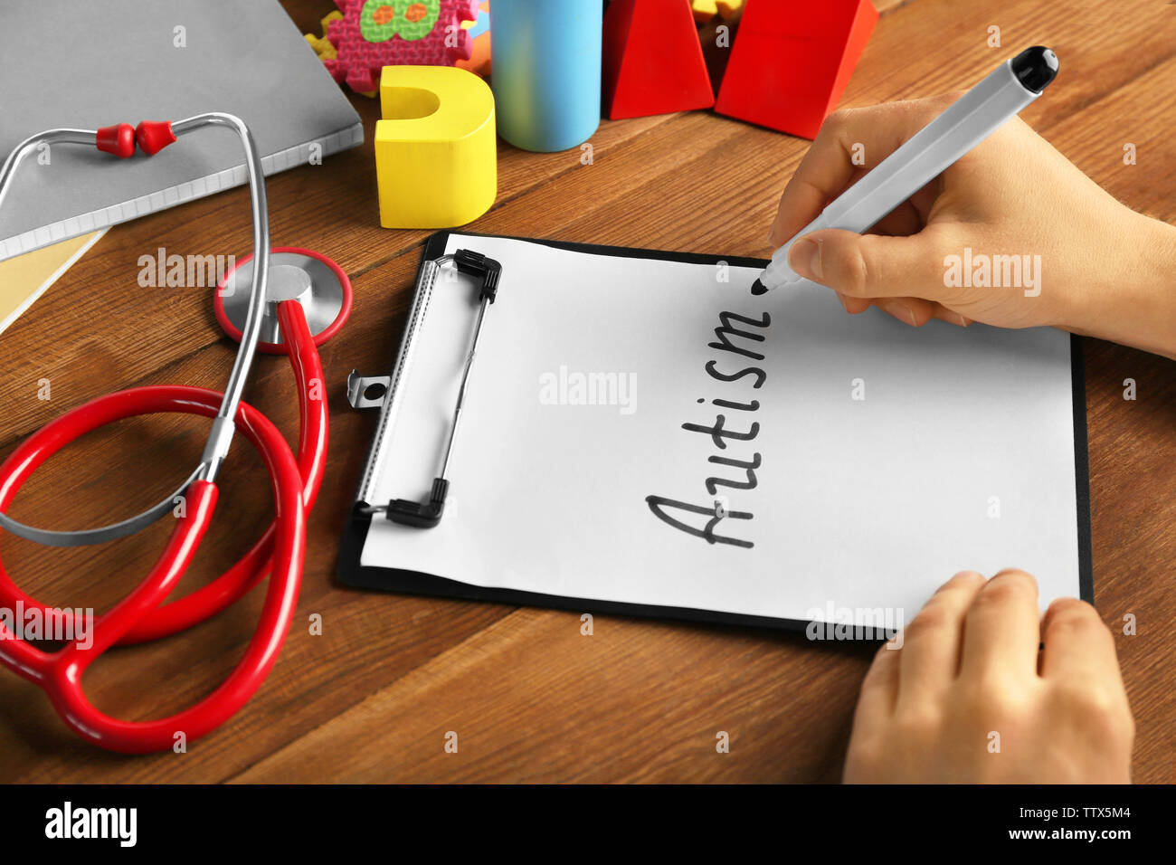 Human hand writing word AUTISM on paper Stock Photo - Alamy