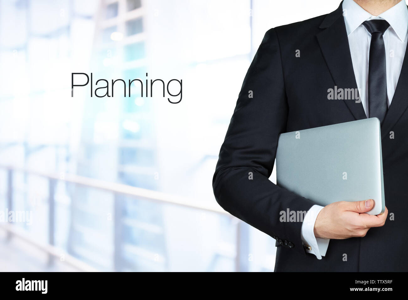 Close up of businessman's hands holding laptop and standing near text ...
