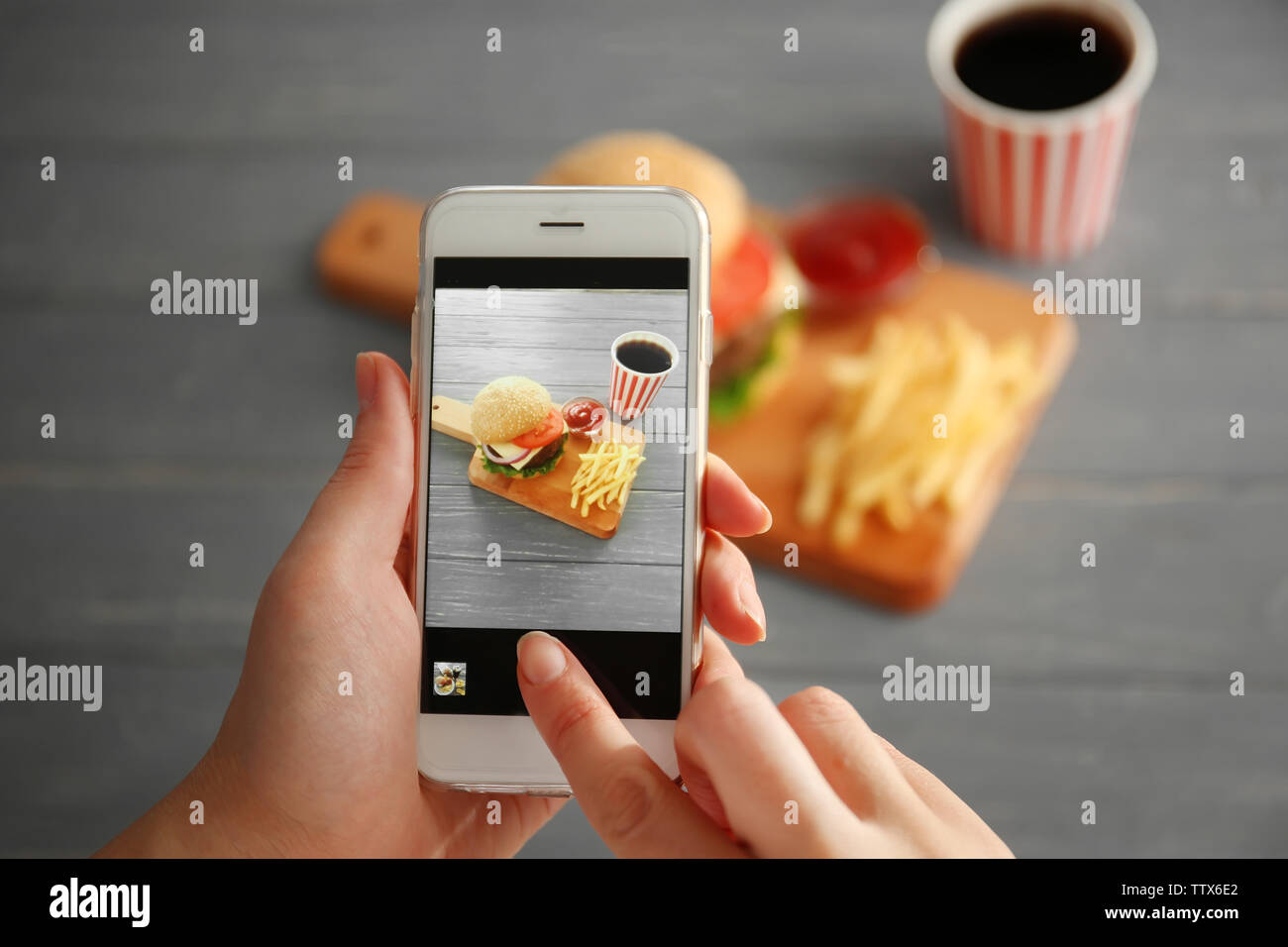 Female hands taking photo of tasty burger with snacks on table Stock ...