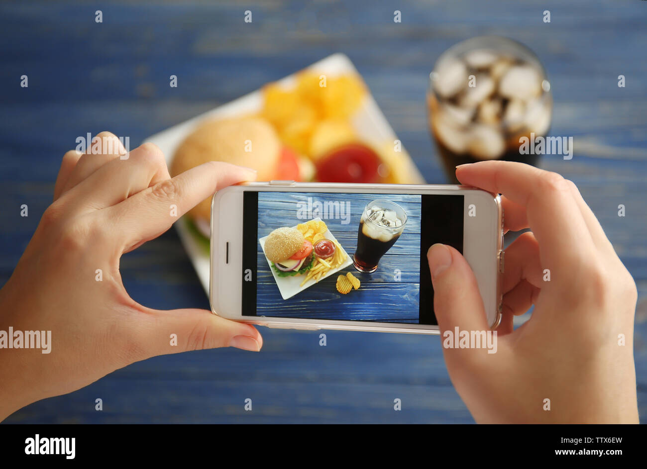 Female hands taking photo of tasty burger with snacks on table Stock ...