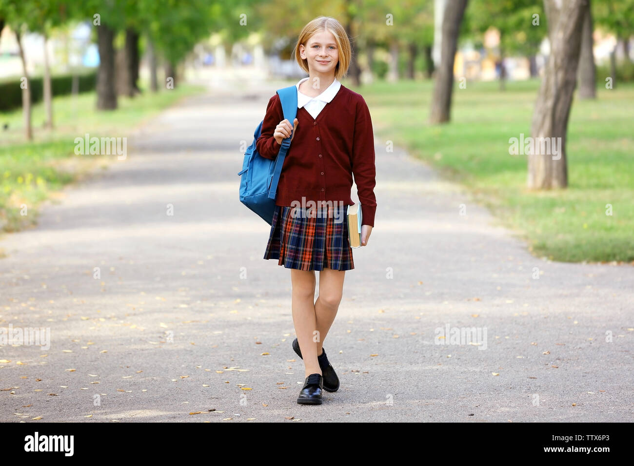 Schoolgirl walking along alley in green park Stock Photo - Alamy