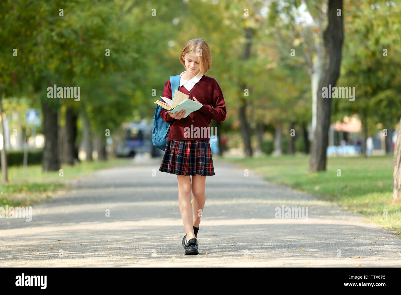 Schoolgirl walking along alley in green park Stock Photo - Alamy
