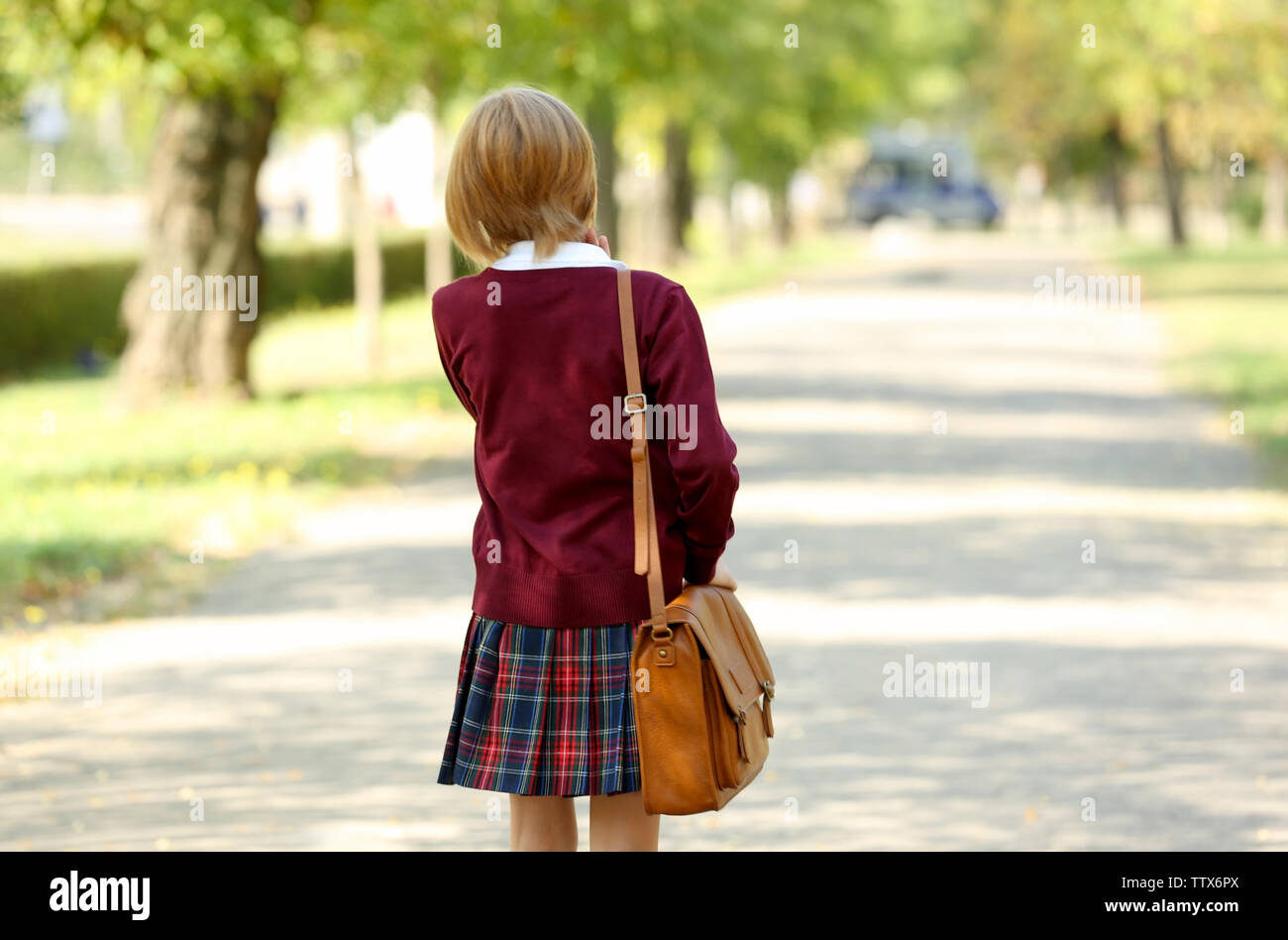 Schoolgirl walking along alley in green park Stock Photo - Alamy
