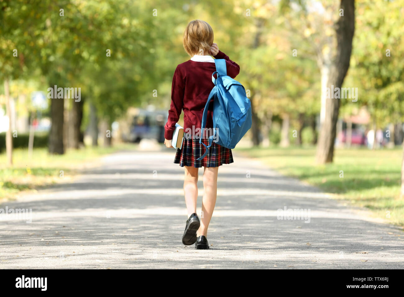 Schoolgirl walking along alley in green park Stock Photo - Alamy