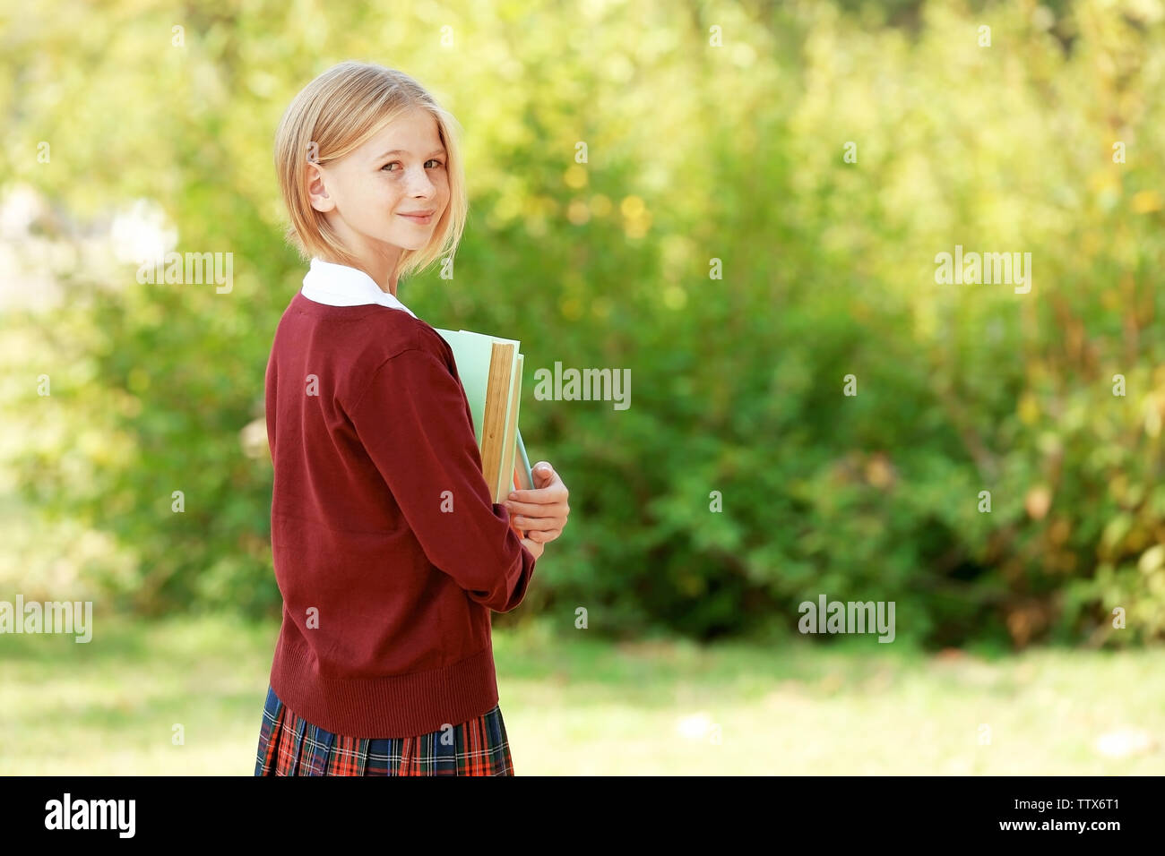 Schoolgirl with books outdoors on blurred background Stock Photo - Alamy