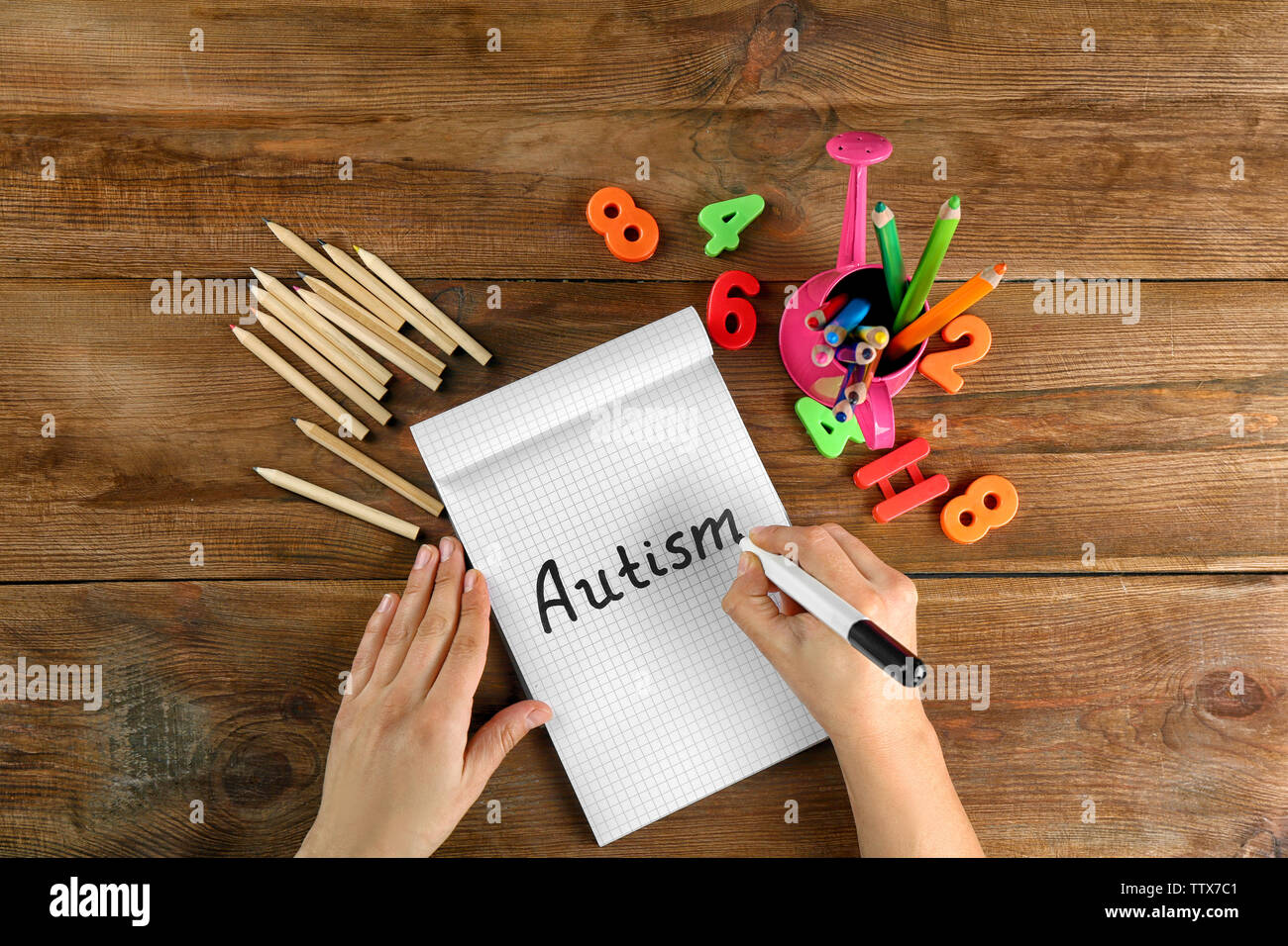 Autism. Hands writing the word in notebook on wooden background Stock ...