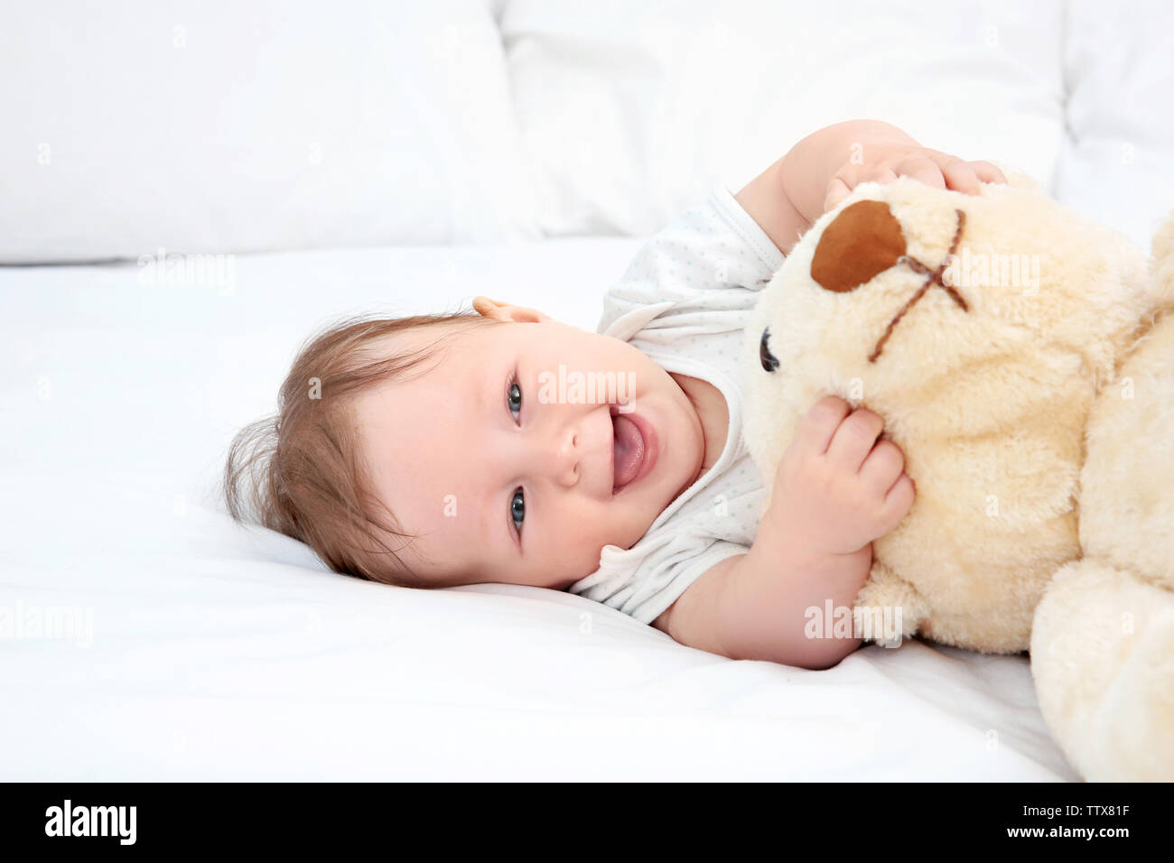 Cute baby playing with teddy bear on bed Stock Photo - Alamy