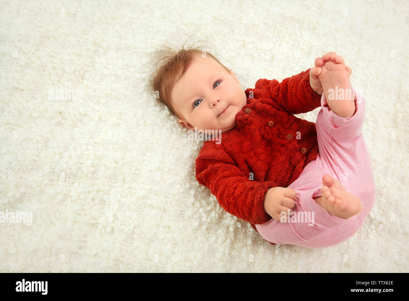 Cute baby in red clothes on blanket Stock Photo - Alamy