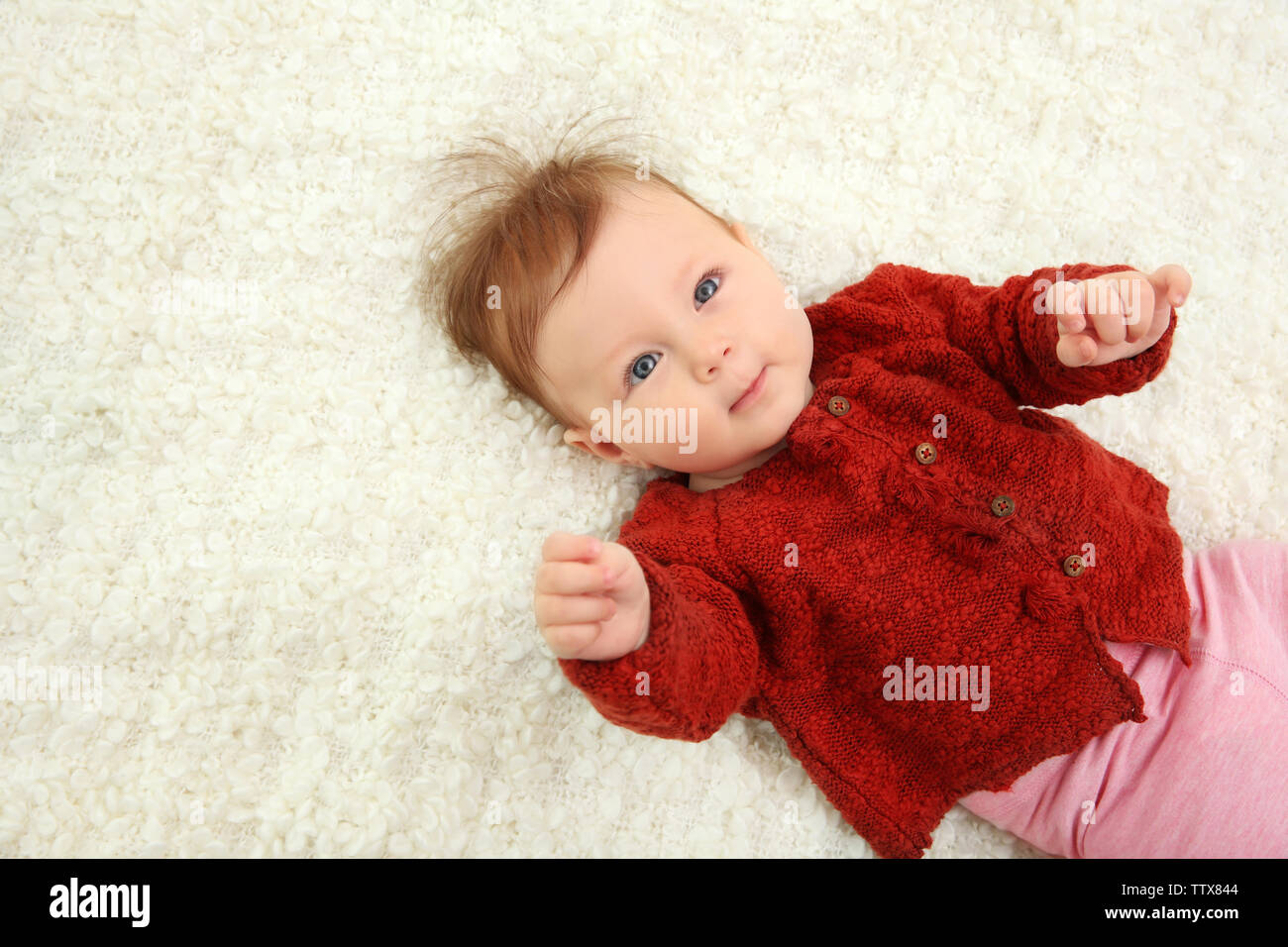 Cute baby in red clothes on blanket Stock Photo - Alamy