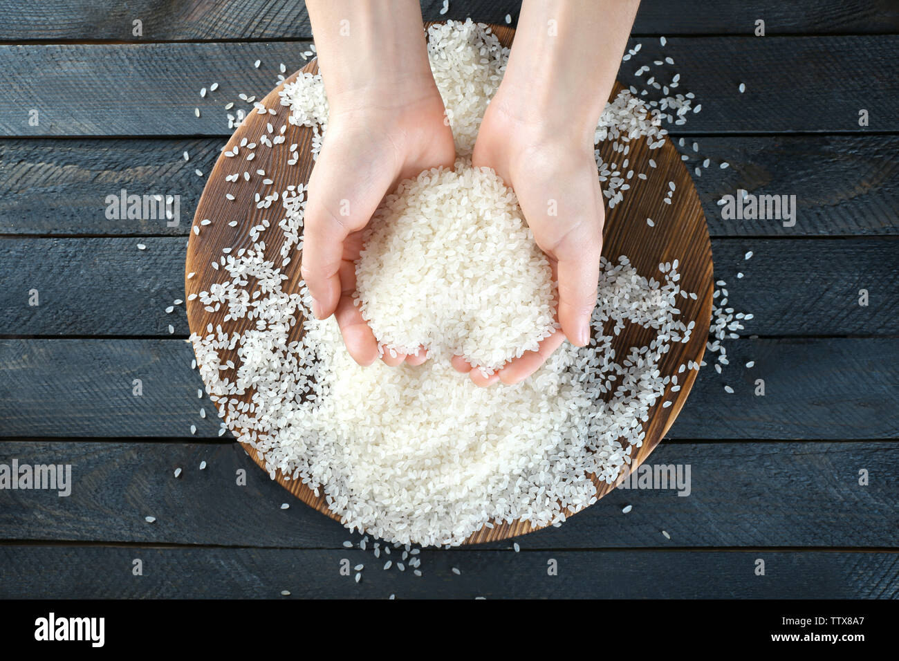 Female hands full of white rice on wooden background Stock Photo - Alamy