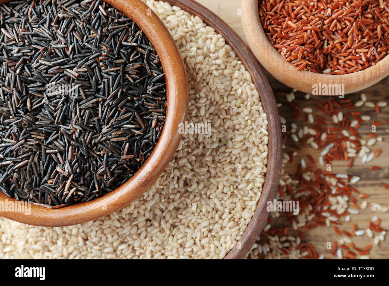 Different types of rice in bowls on wooden table, top view Stock Photo ...