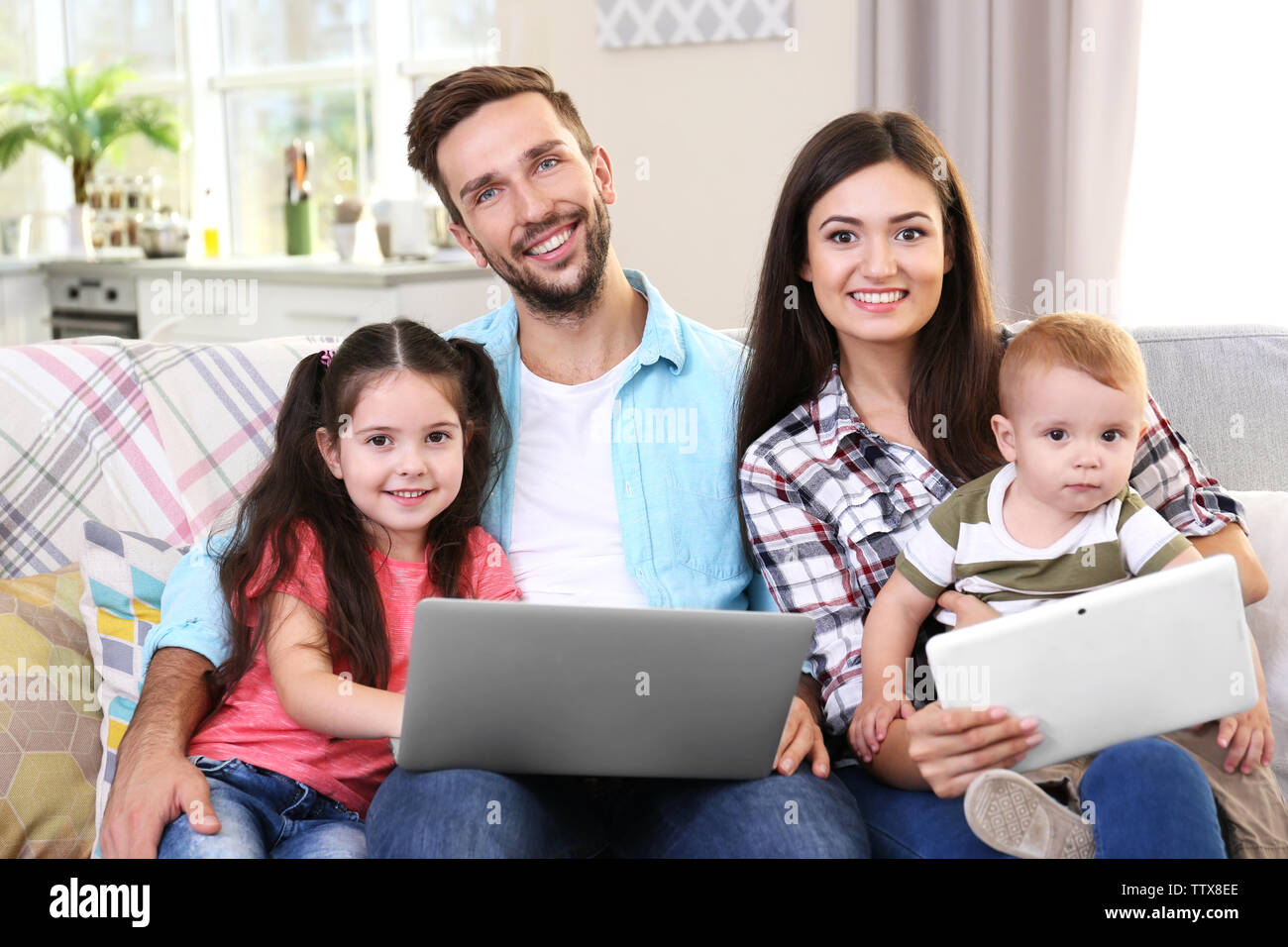 Happy family with gadgets on couch Stock Photo - Alamy