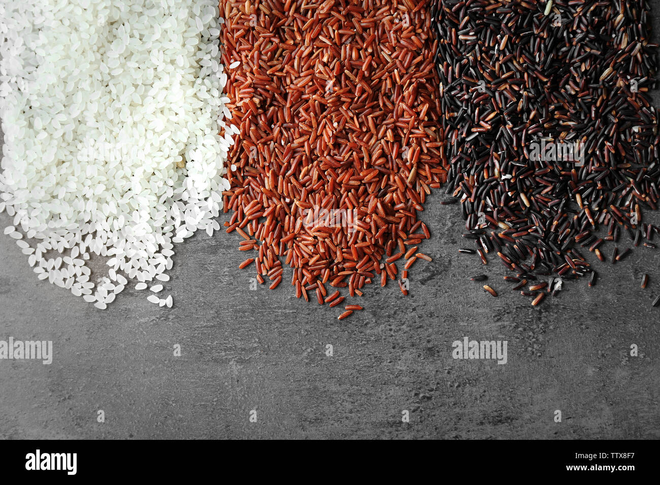 Different types of rice on grey textured background Stock Photo - Alamy