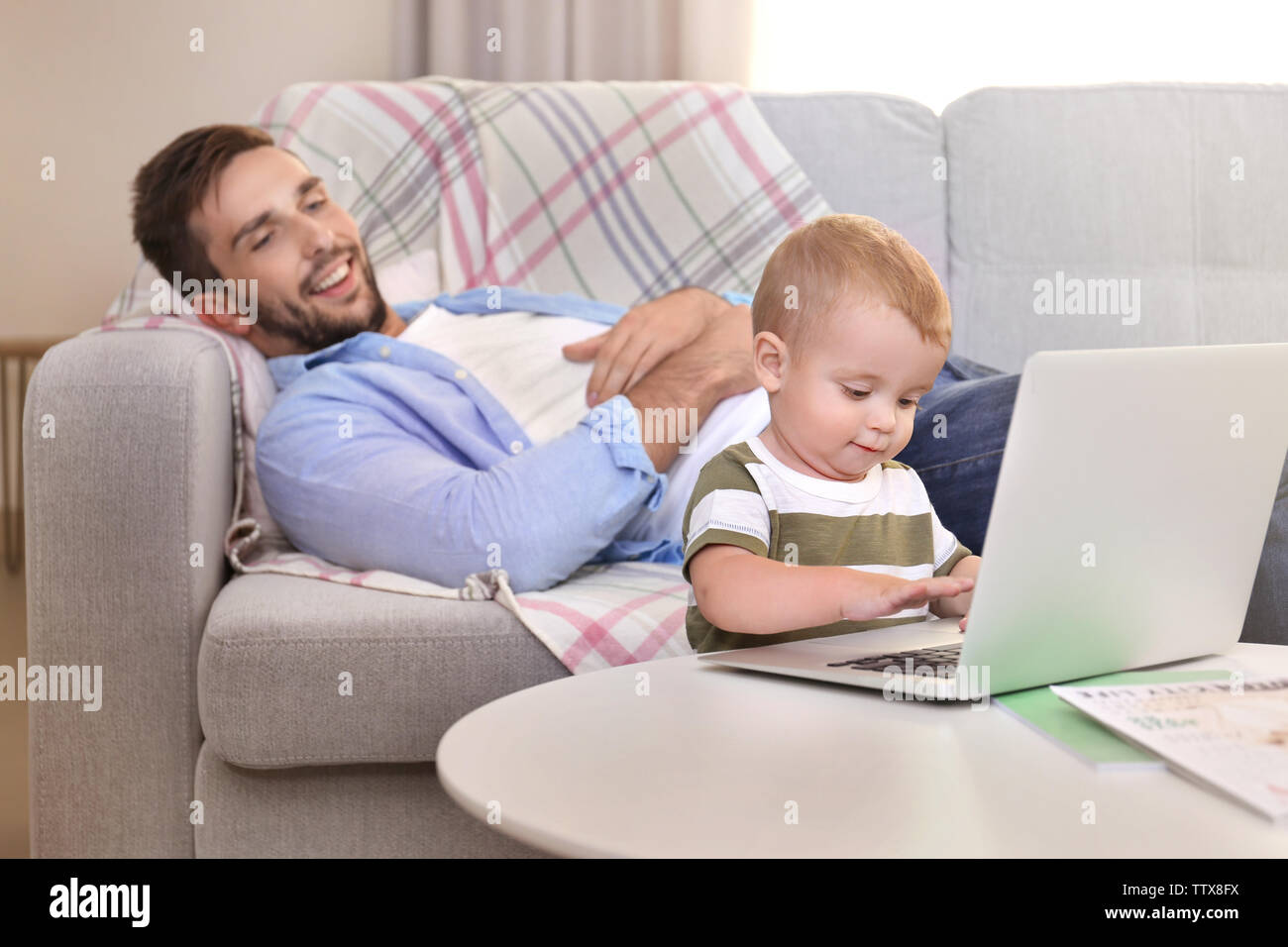 Cute baby boy using laptop under father control Stock Photo - Alamy