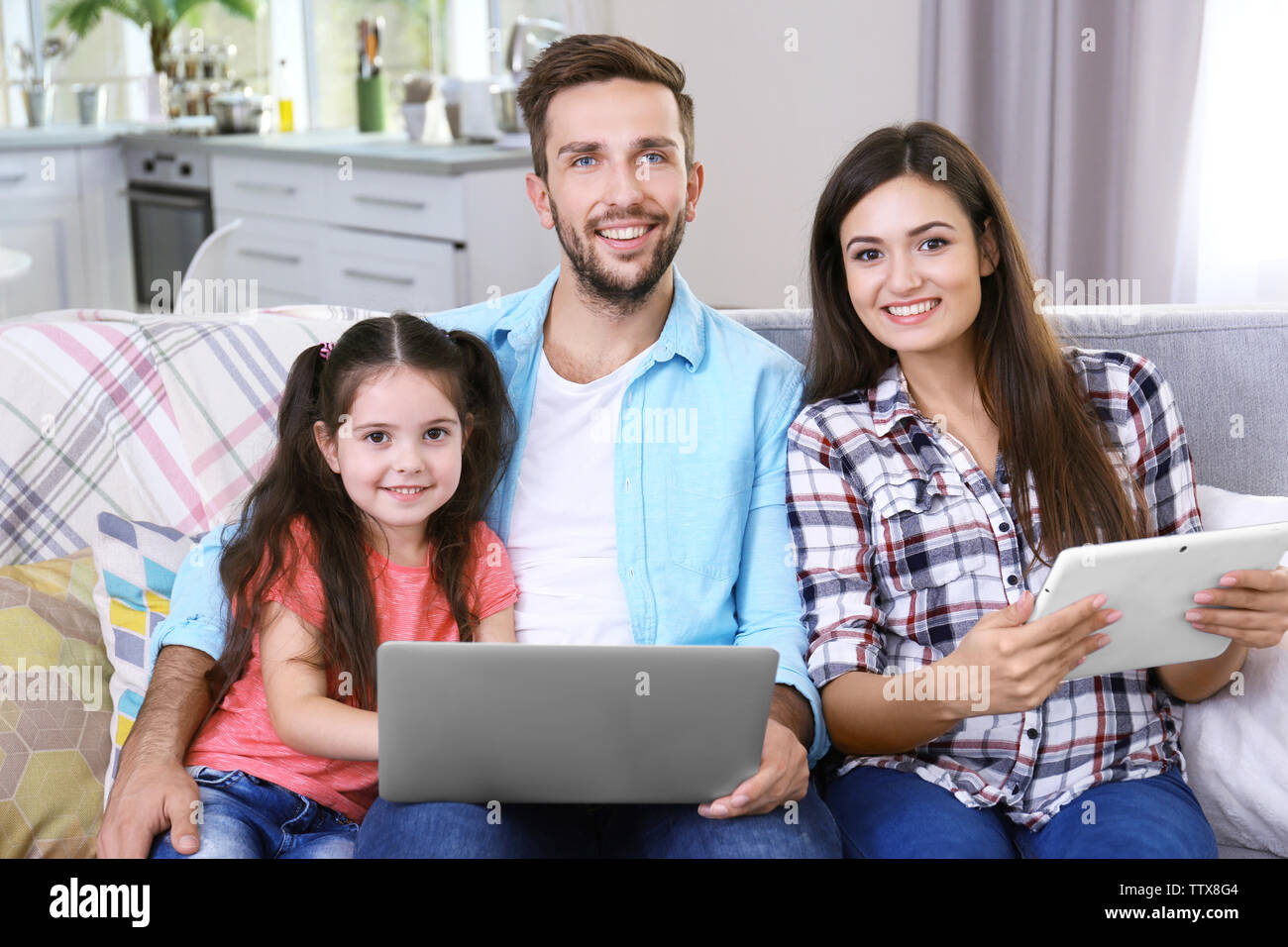Happy family with gadgets on couch Stock Photo - Alamy