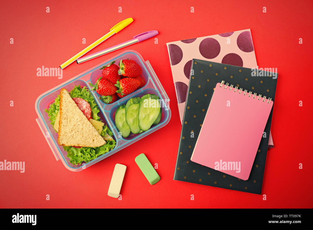 Lunch box with food and stationery on red background, top view Stock ...