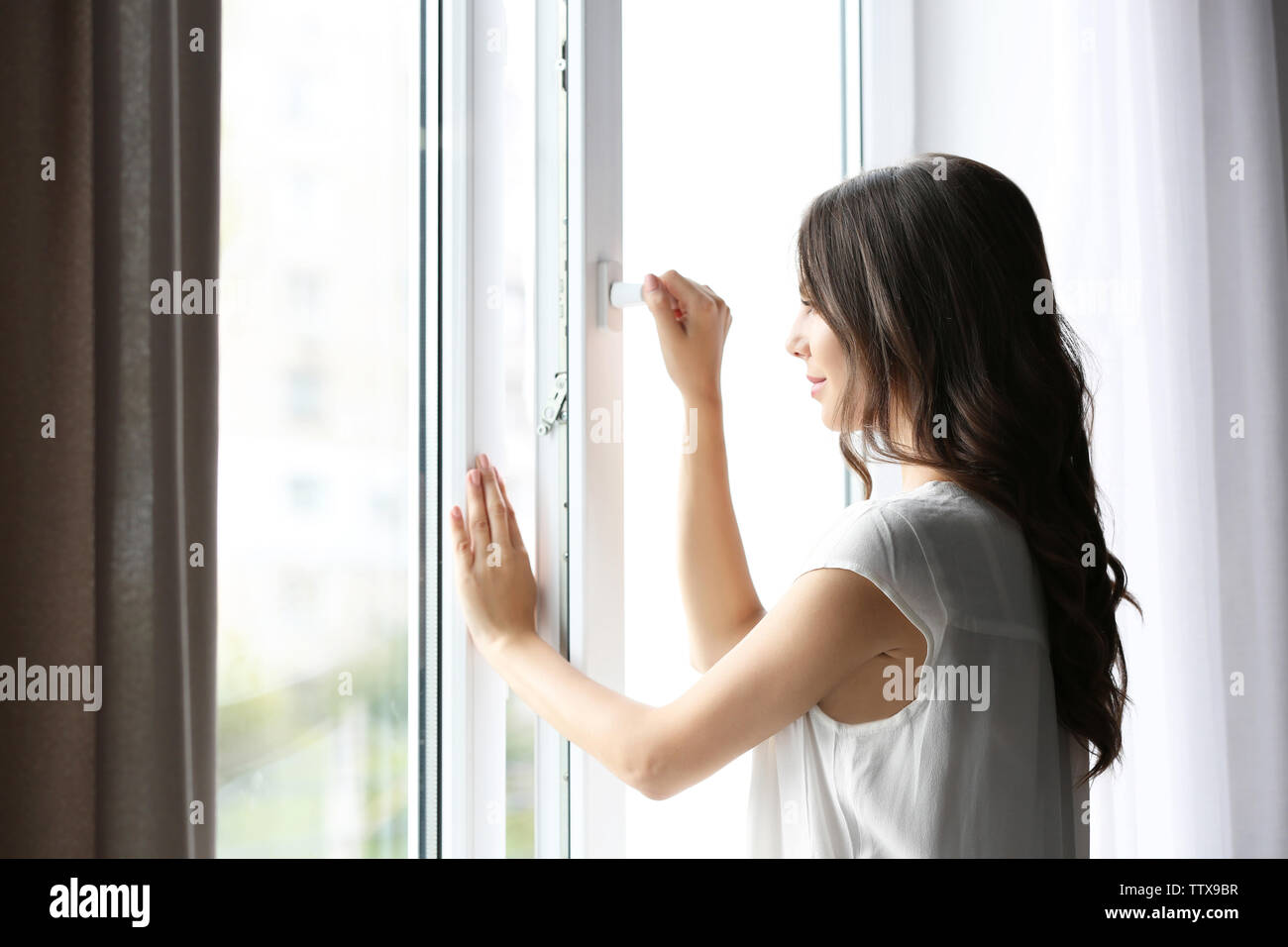 Beautiful woman opening window in the morning Stock Photo - Alamy