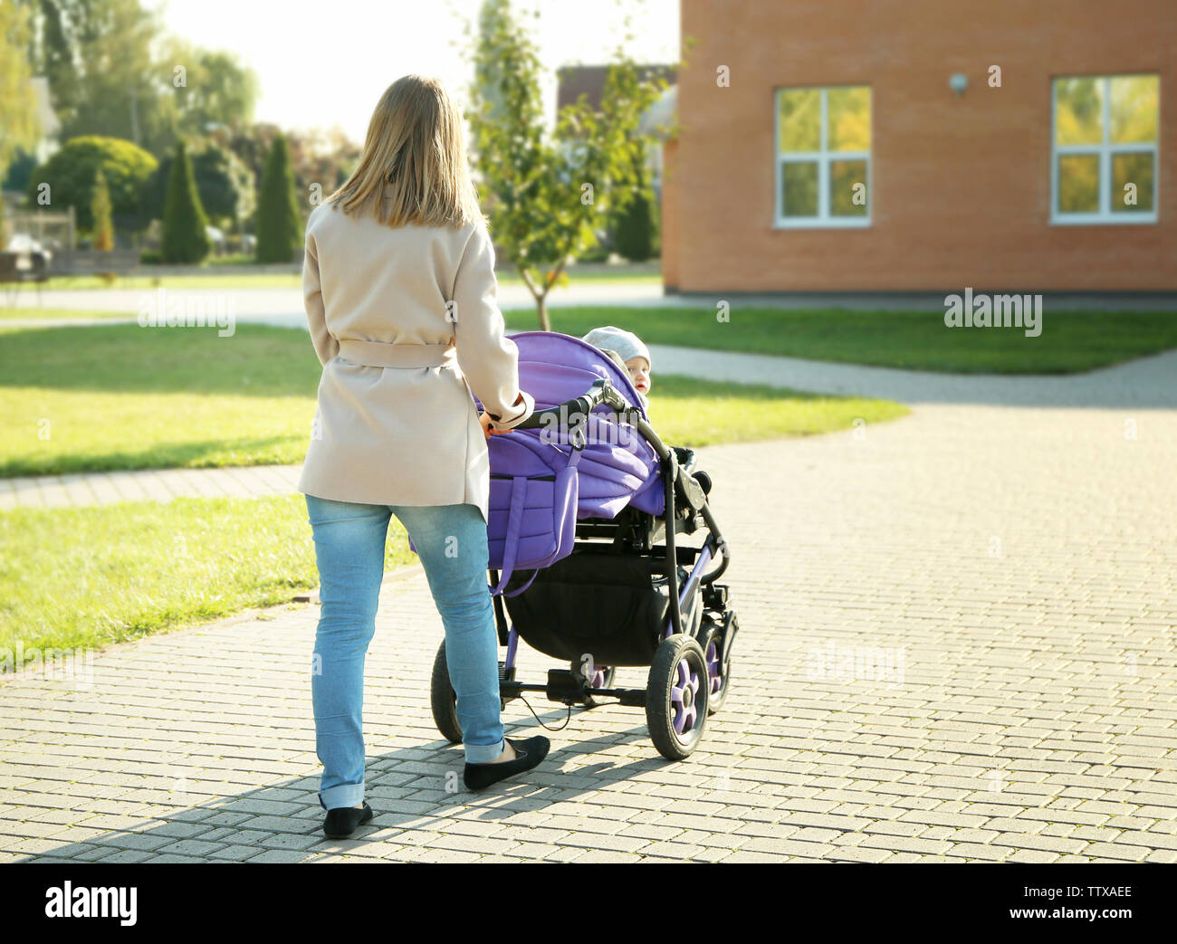 Woman with baby stroller walking in green park Stock Photo - Alamy