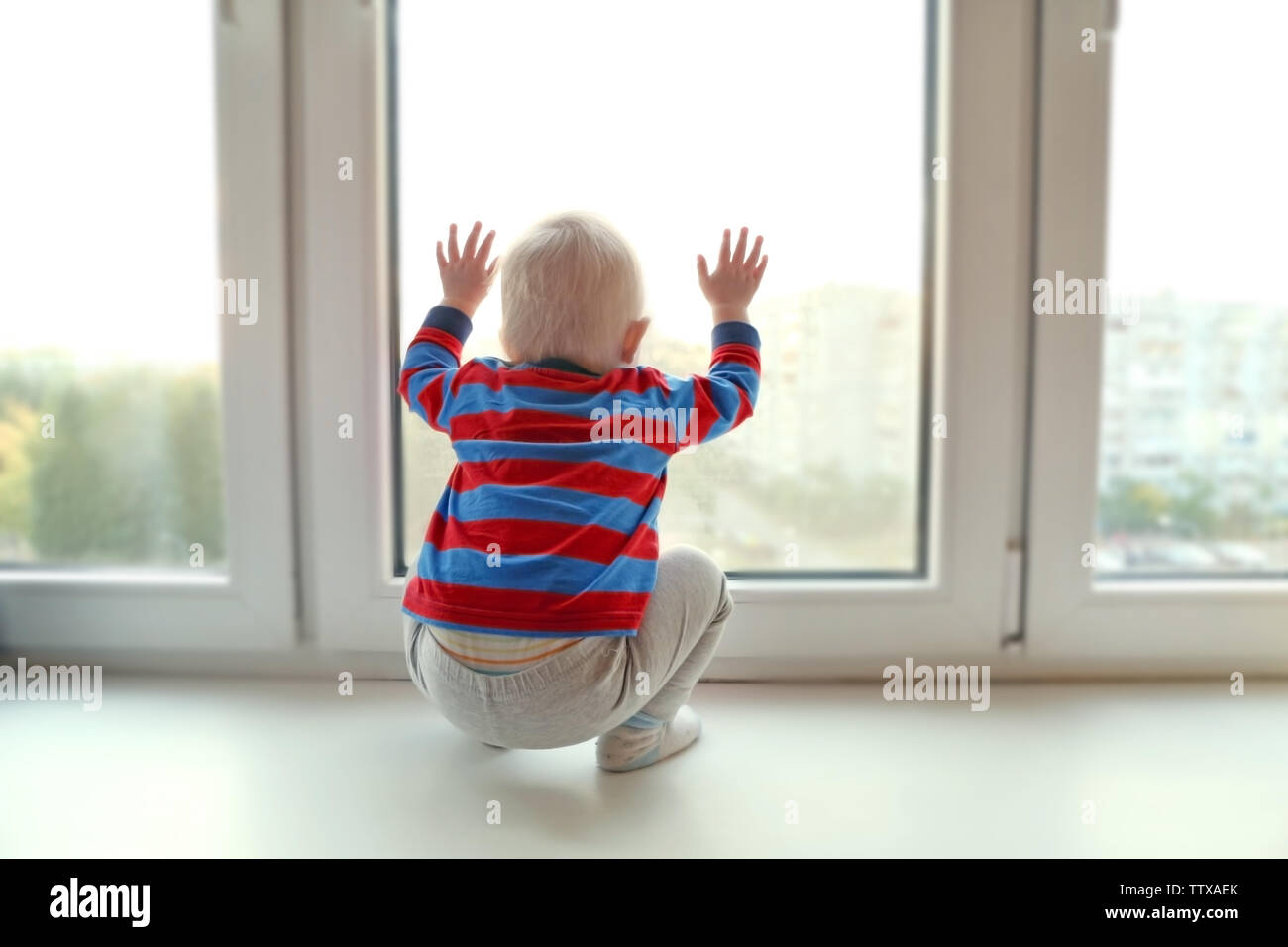 Cute little boy looking out of window Stock Photo - Alamy
