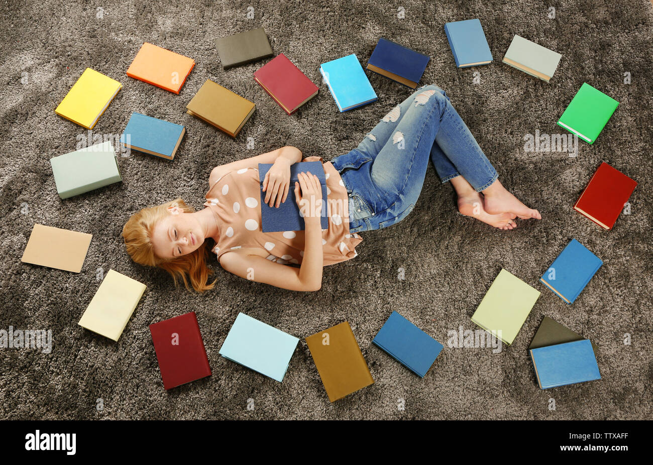 Sleeping girl with books on carpet Stock Photo - Alamy