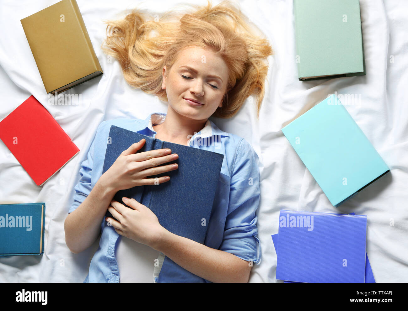 Sleeping girl with books on bed Stock Photo - Alamy