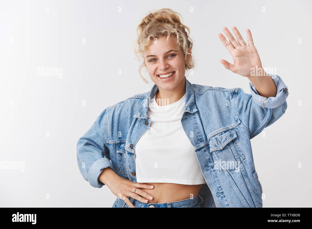 Cheerful energized friendly young girl smiling broadly waving you say ...