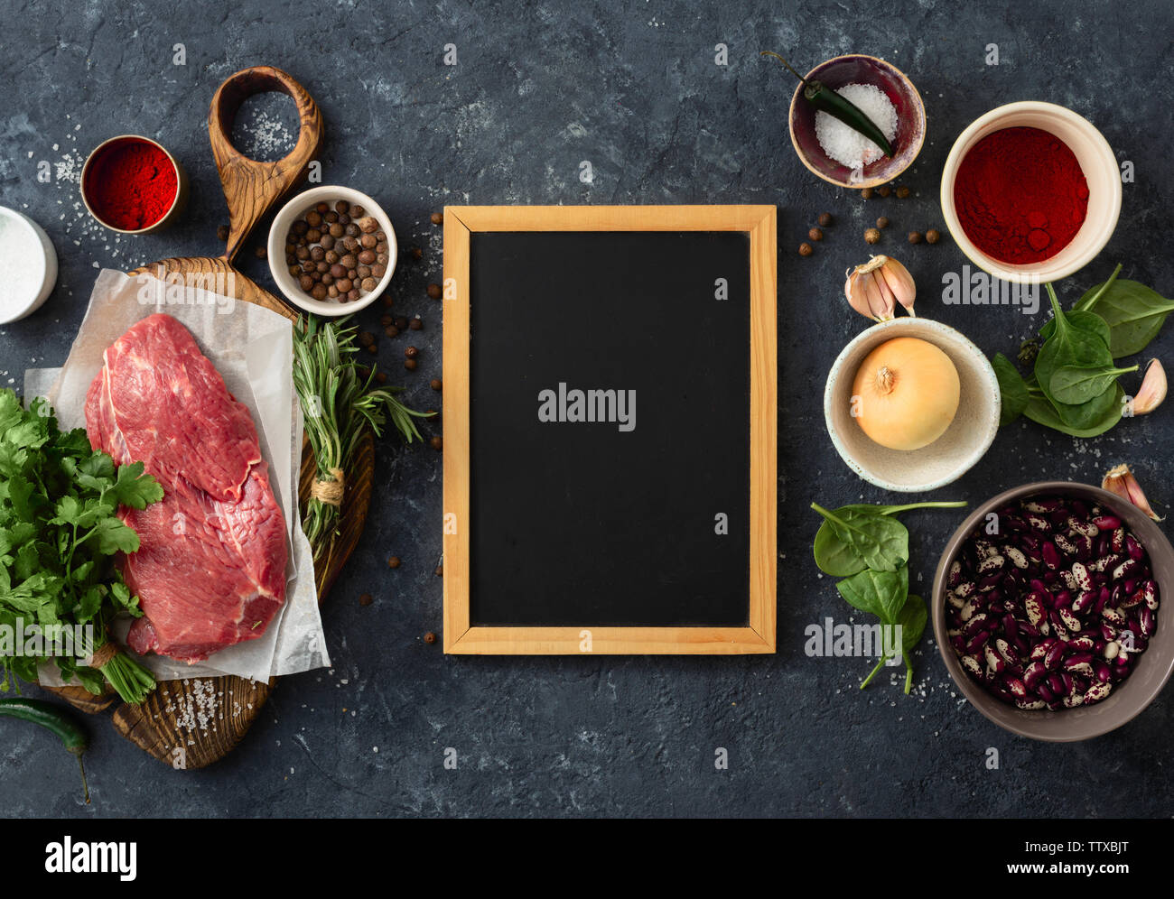 Cooking table with blank chalk board and beef meat, vegetables, spices ...