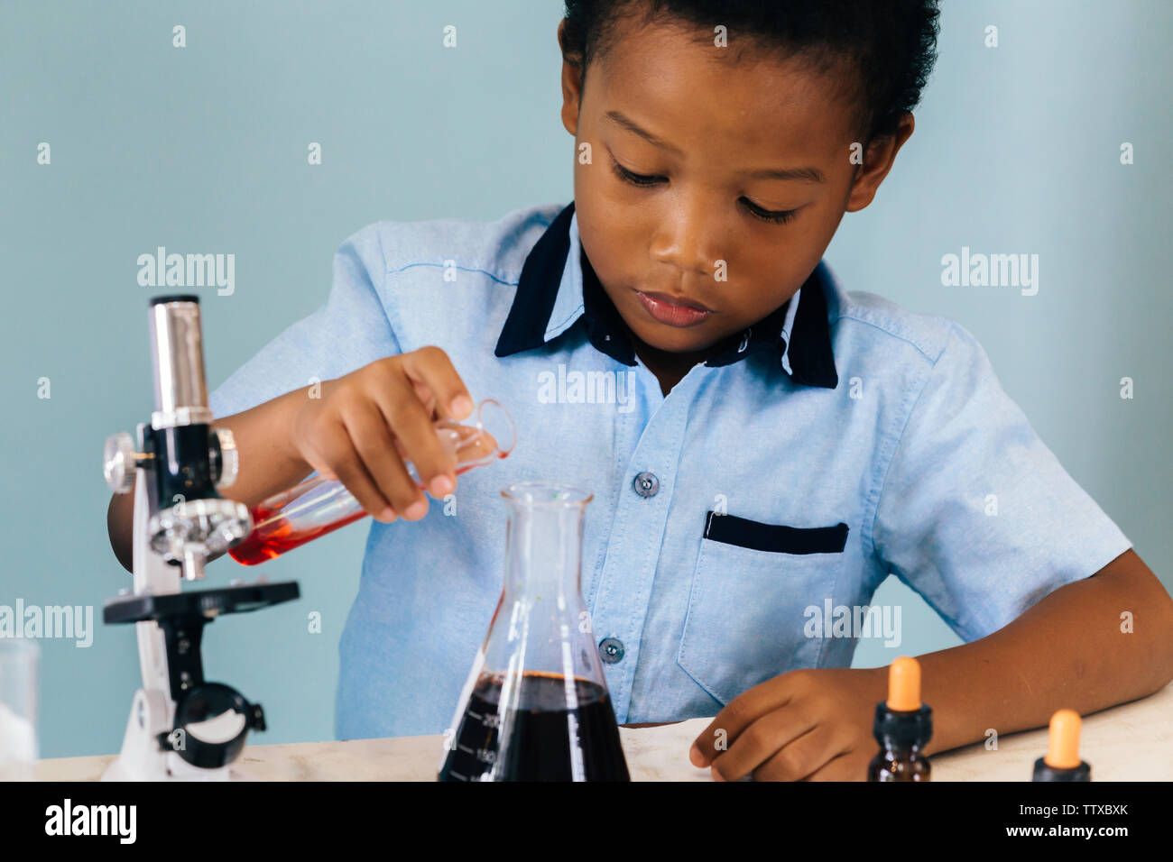 African American boy mixing potion from chemicals while learning ...