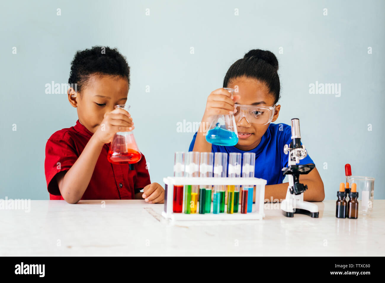 African American curious pretty clever kids sitting with flasks ...