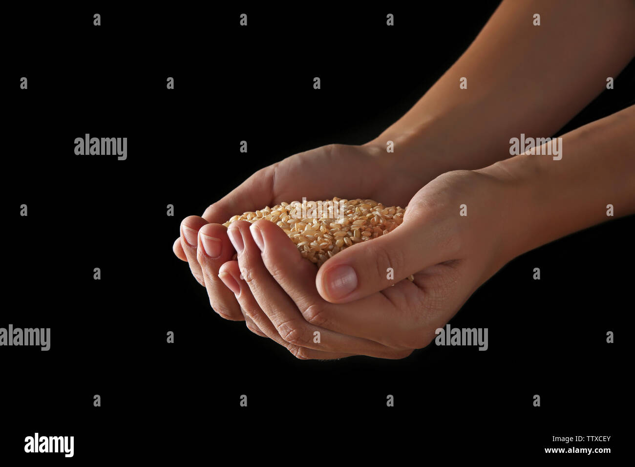 Female hands holding rice on black background Stock Photo - Alamy