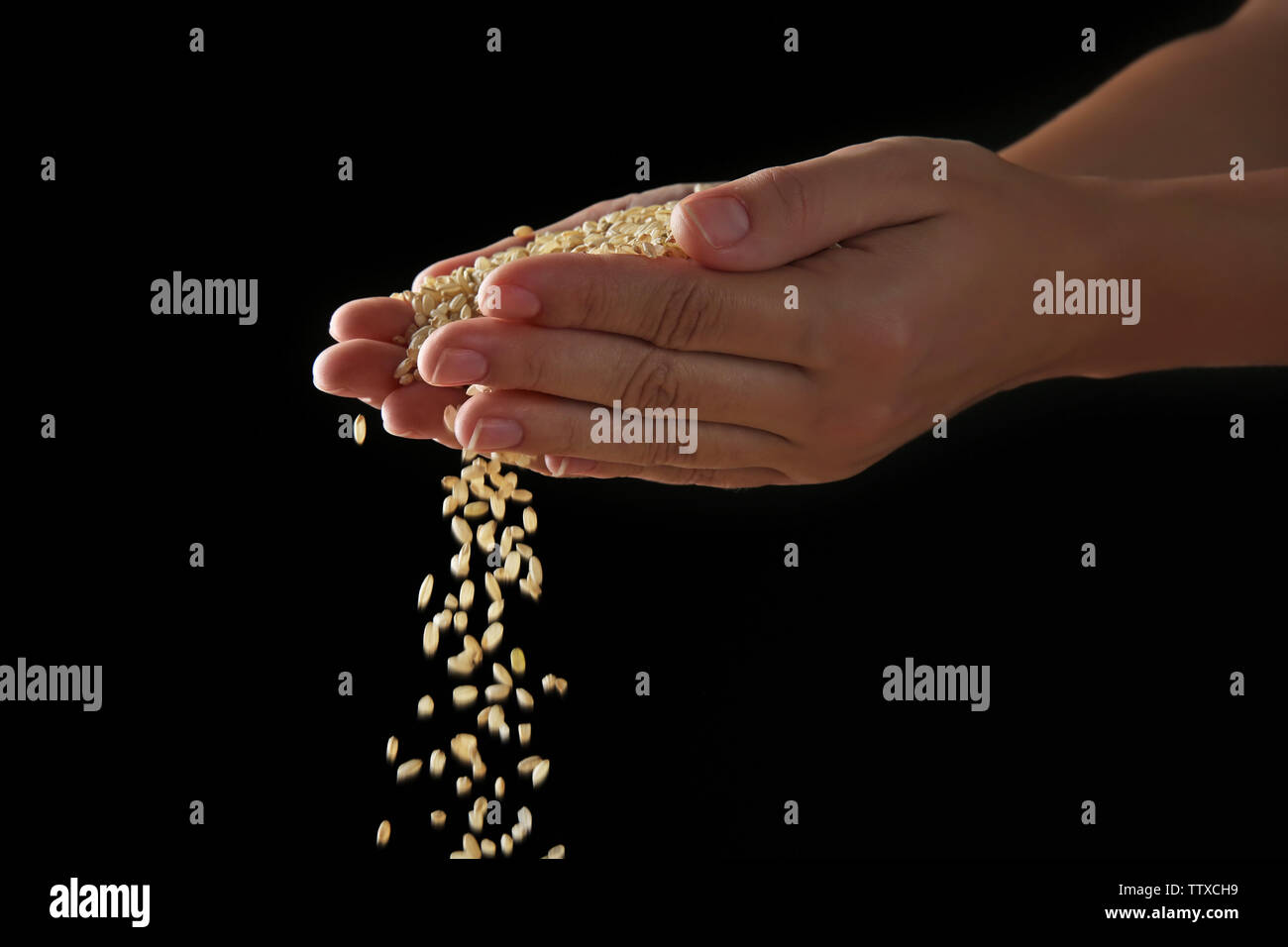 Female hands holding rice on black background Stock Photo - Alamy