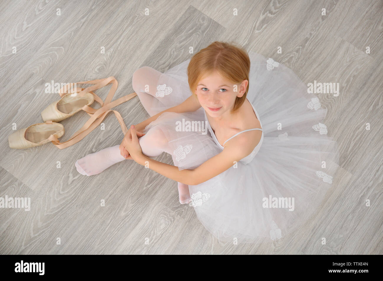 Small ballerina dancer sitting on floor Stock Photo - Alamy