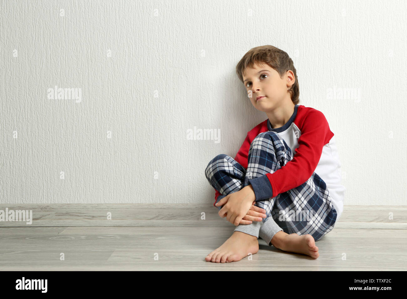 Cute little boy sitting on floor in empty room Stock Photo - Alamy