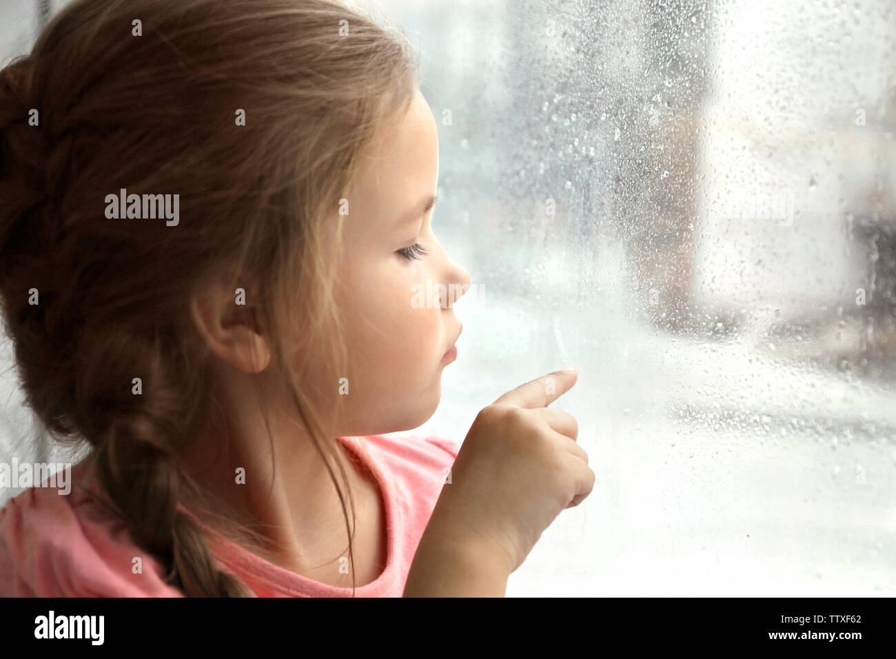 Close up view of little girl looking out of window Stock Photo - Alamy