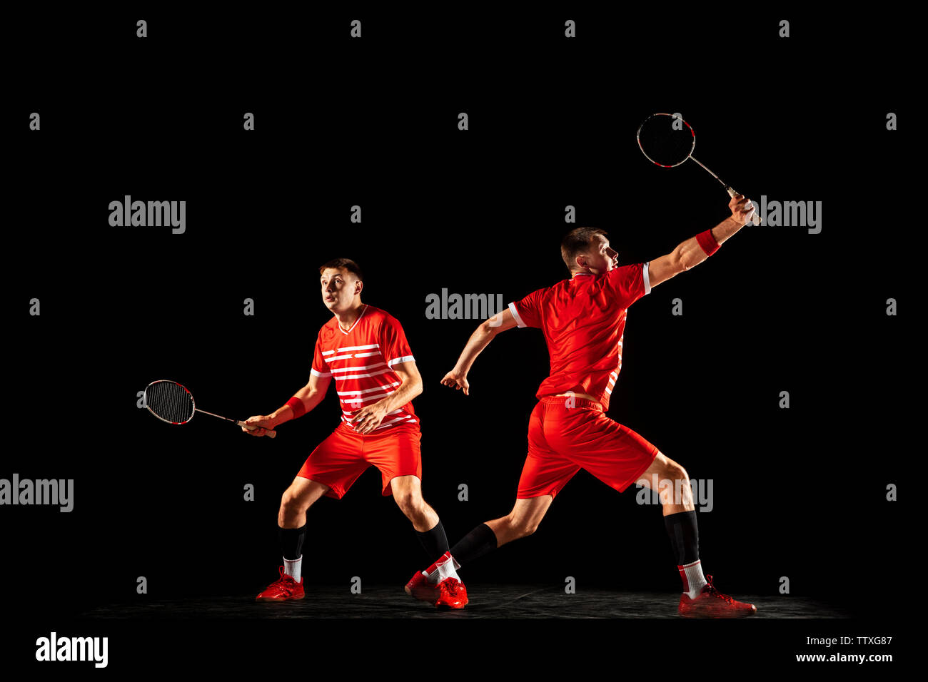 Young man playing badminton isolated on black background in mixed light ...