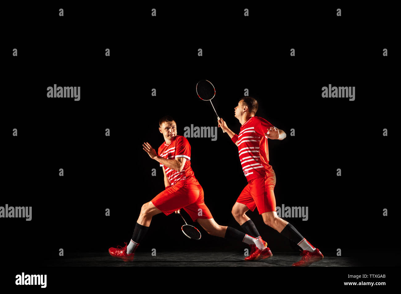 Young man playing badminton isolated on black background in mixed light ...