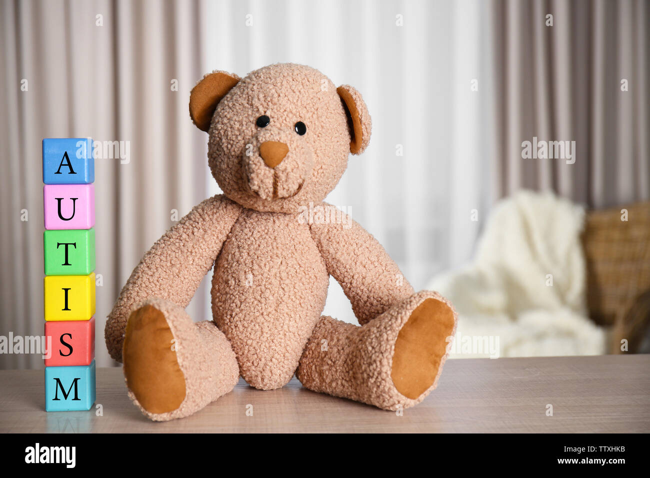 Colorful wooden cubes with Teddy bear on curtains background. Autism ...