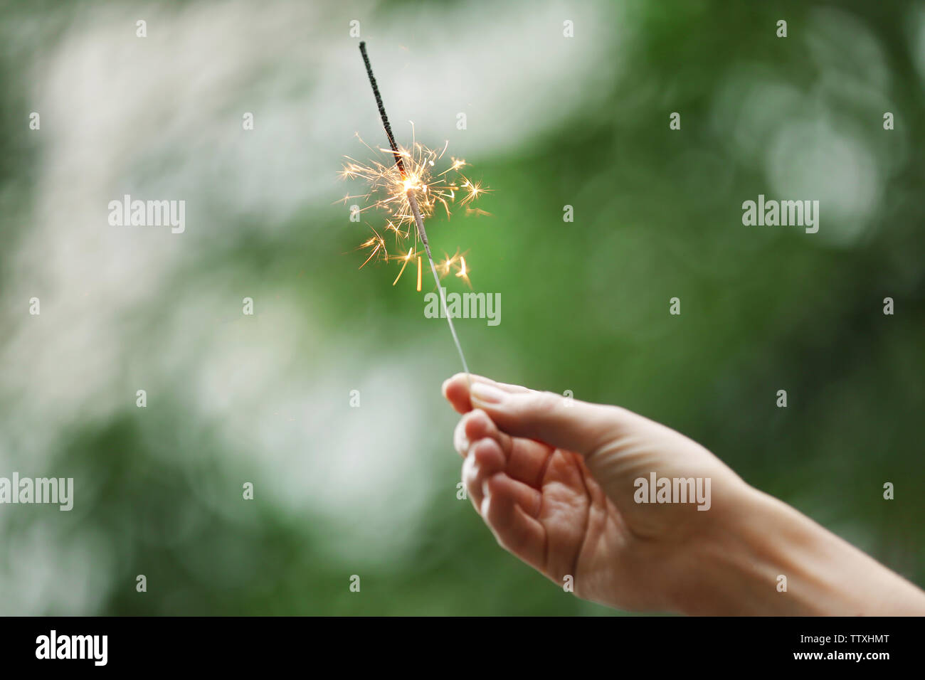Female hand holding sparkler on blurred background Stock Photo - Alamy