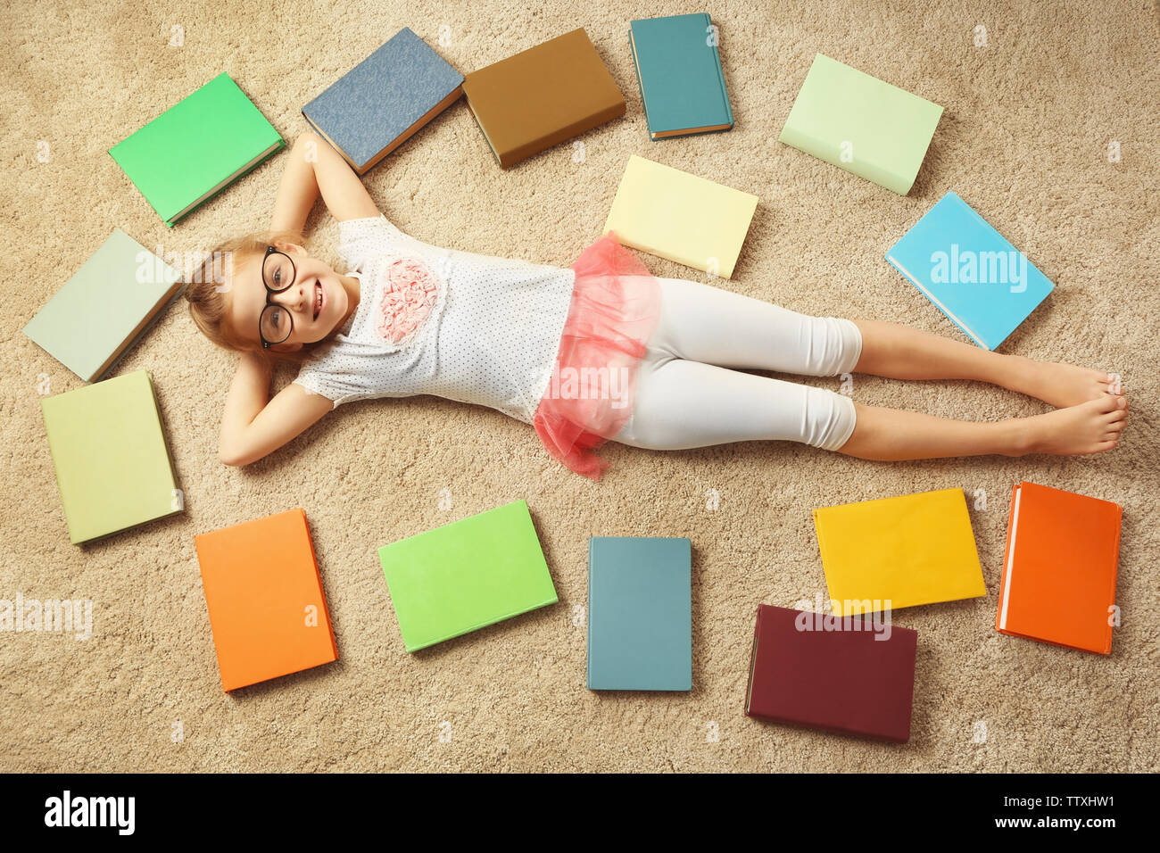 Cute girl with books lying on floor Stock Photo - Alamy