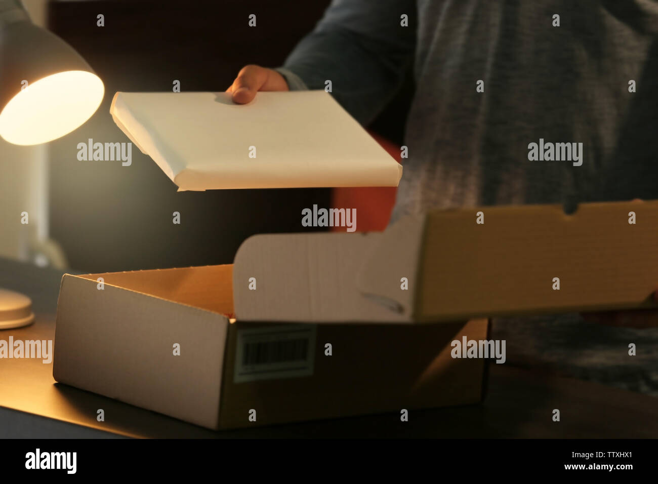 Courier putting parcel in carton box Stock Photo - Alamy