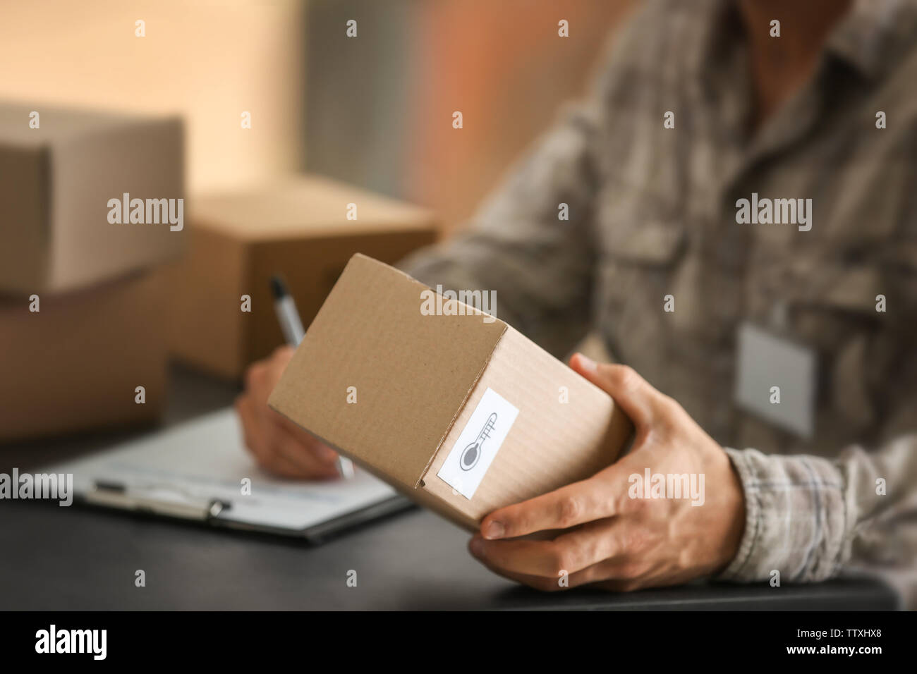 Courier making notes in delivery receipt at table Stock Photo - Alamy