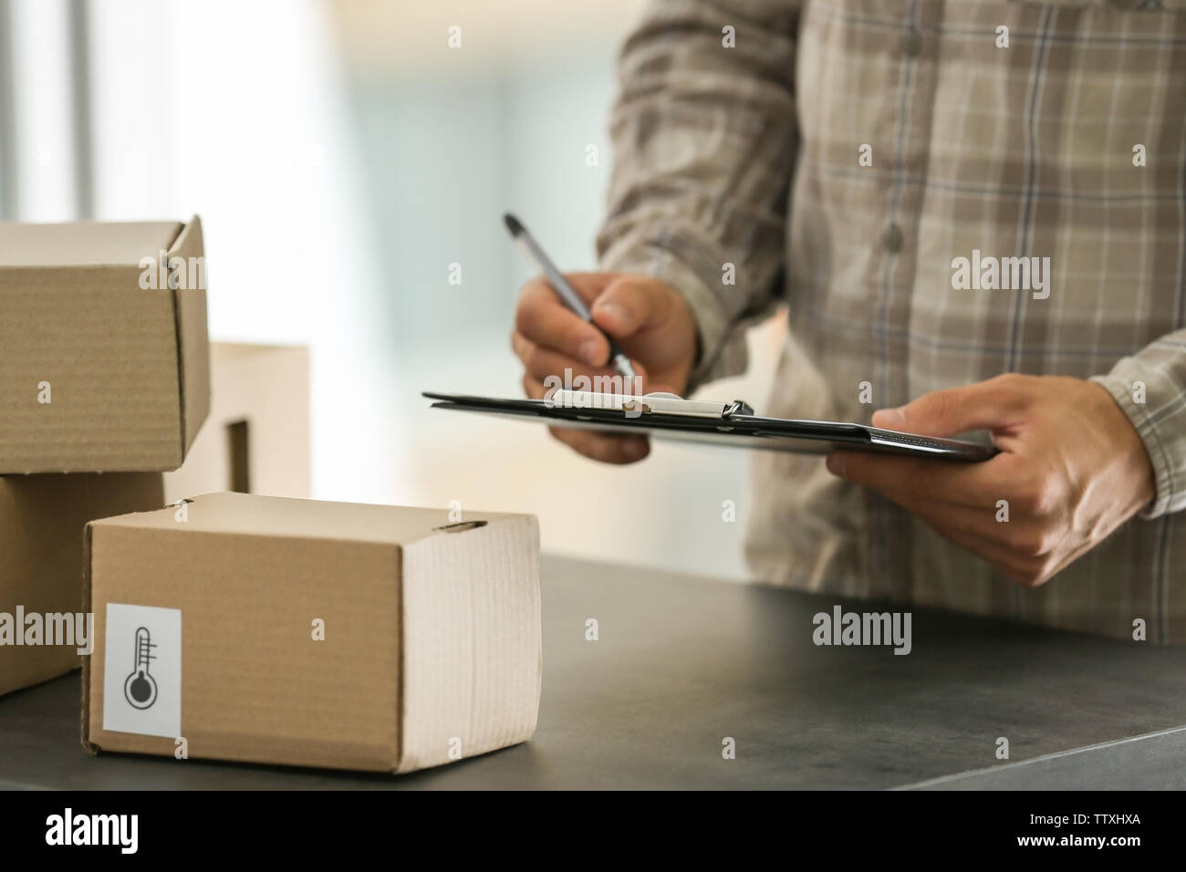 Courier making notes in delivery receipt at table Stock Photo - Alamy