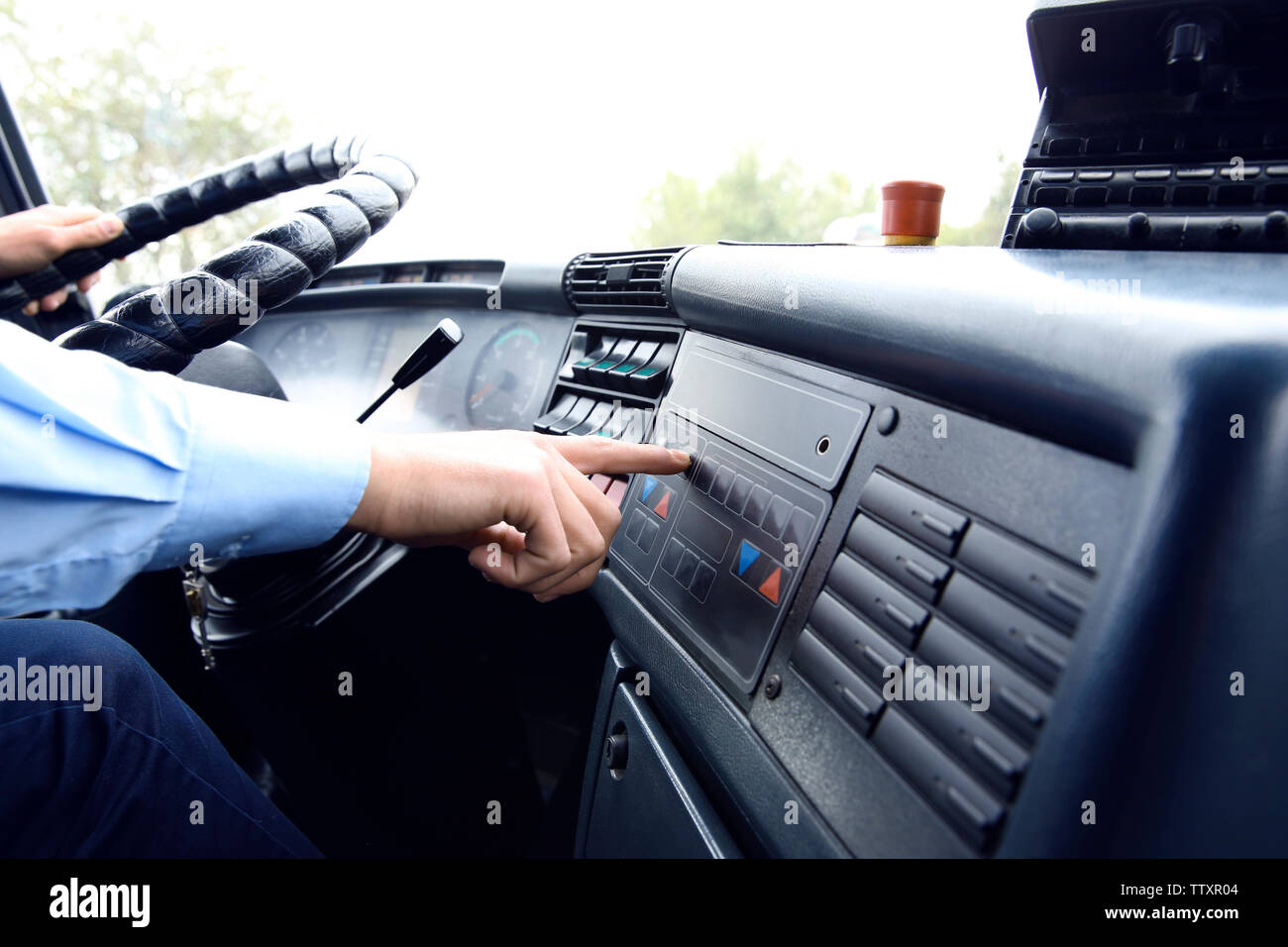 Bus driver pushing button on panel Stock Photo - Alamy